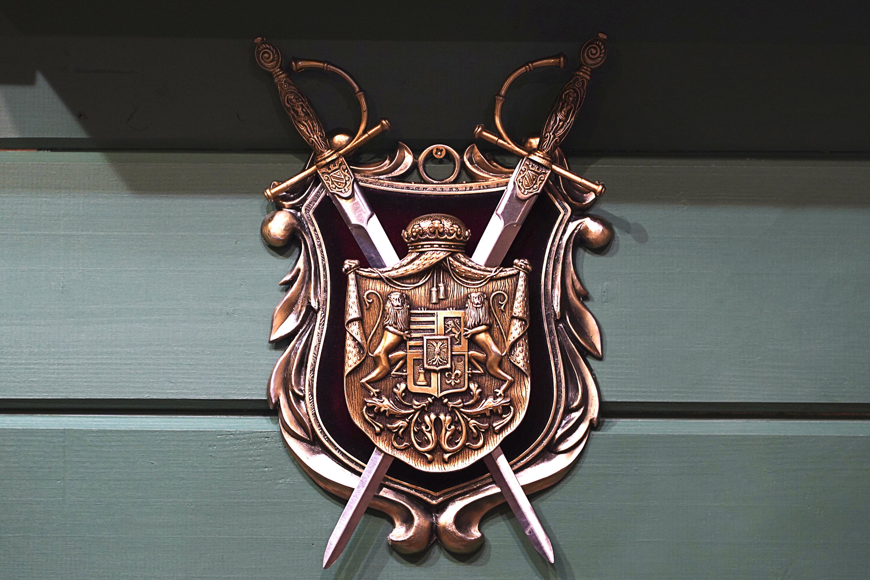 Copper coat of arms with swords on a wooden wall (690996) | Conceptual ...