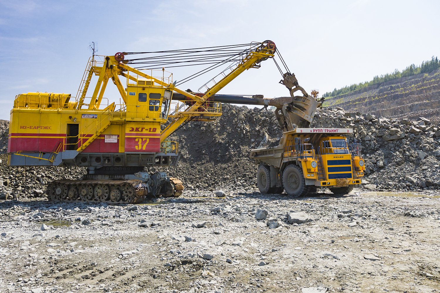 A mining excavator loads a huge truck with granite rock (611679 ...