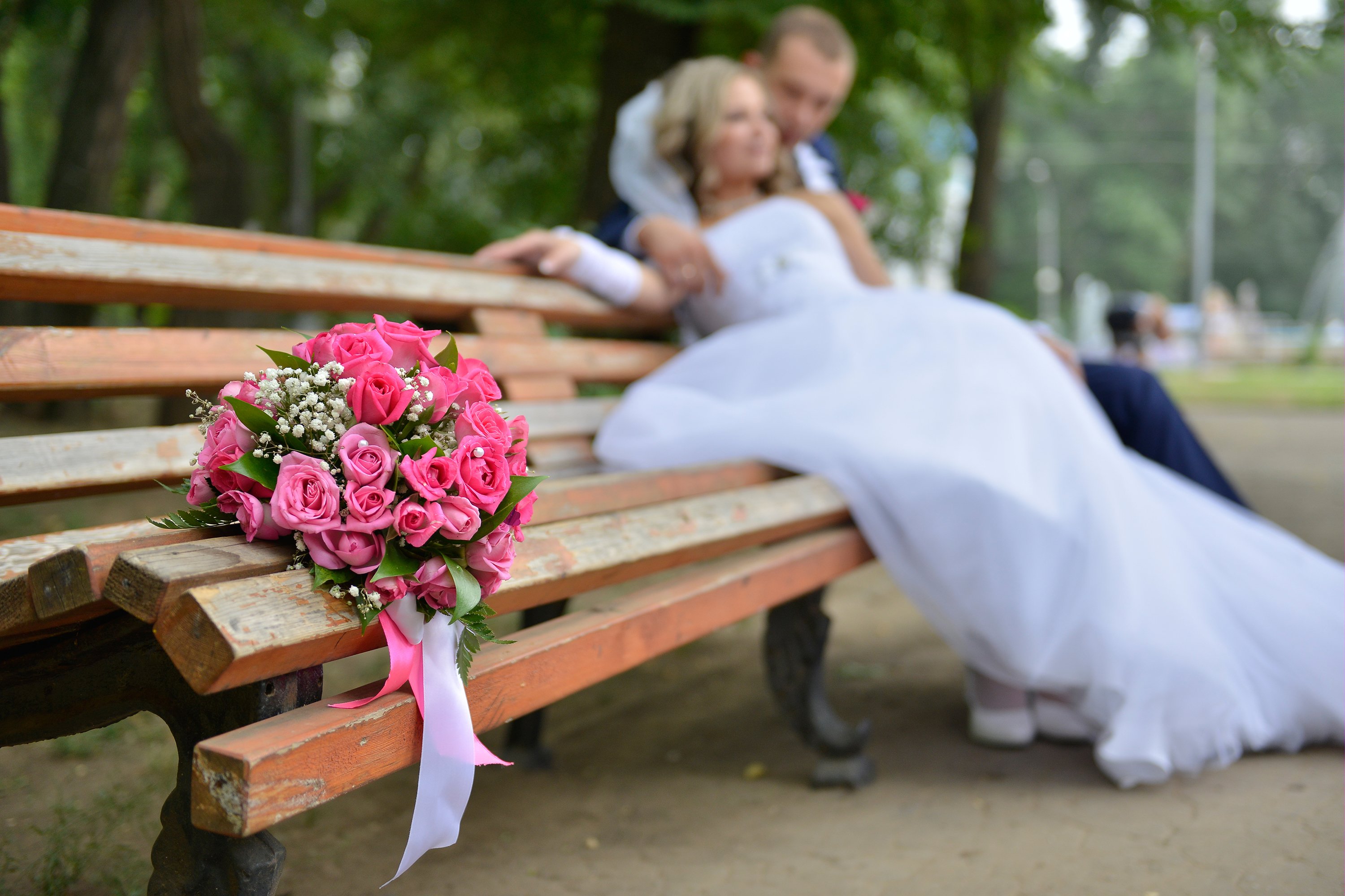 bouquet on wooden bench with bride and groom (640036)