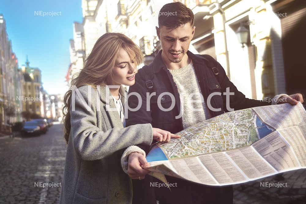 Couple of young tourists reading a map in the city