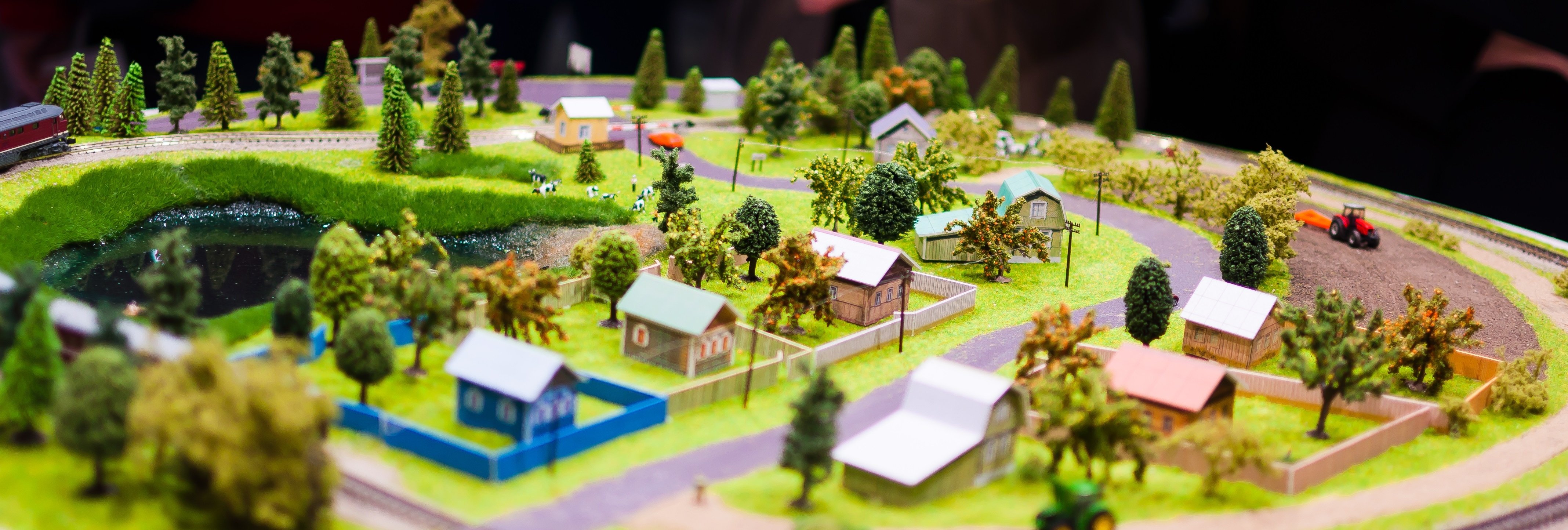 Miniature village. Cows graze near the lake in the village