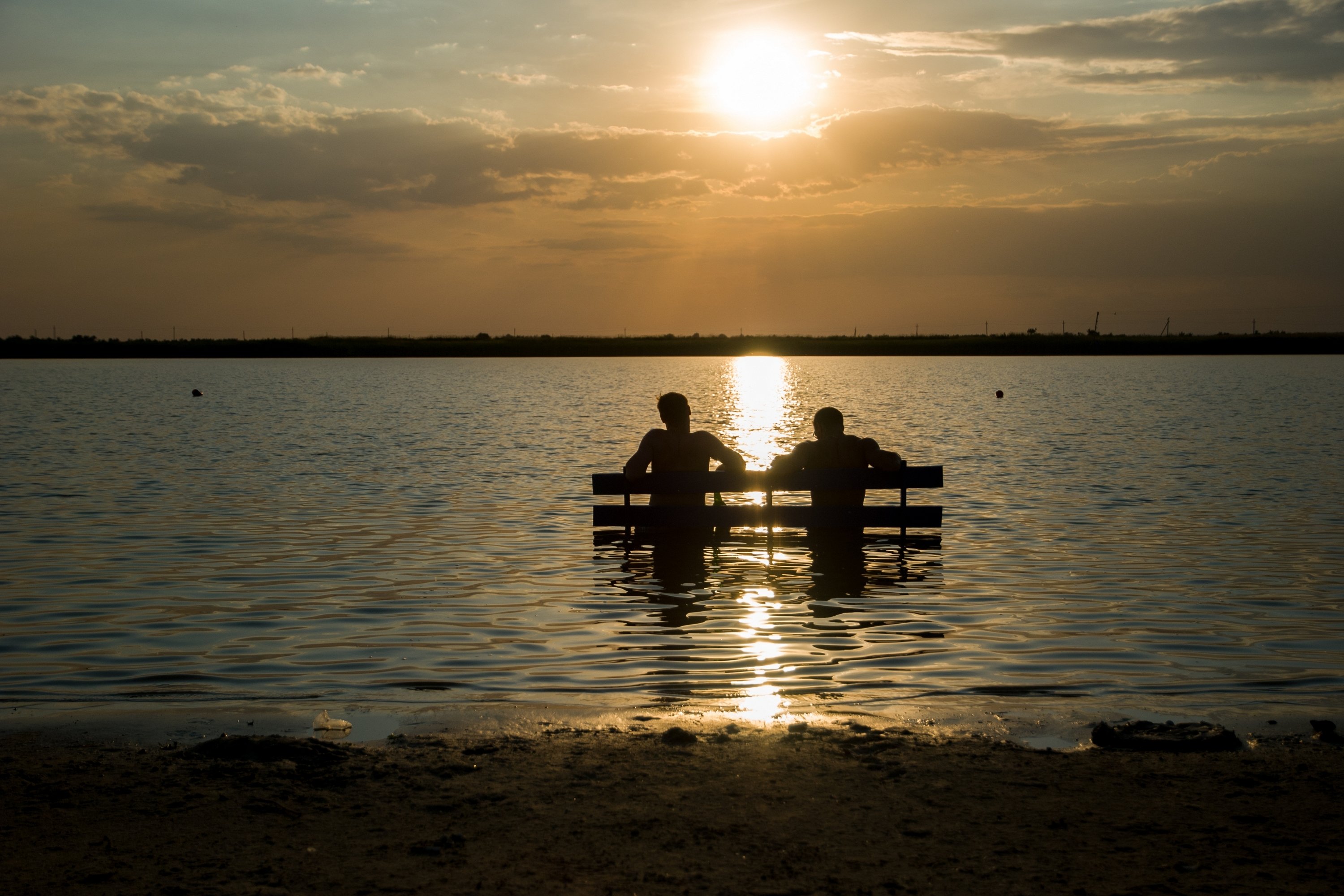 Two men on a bench in the river.