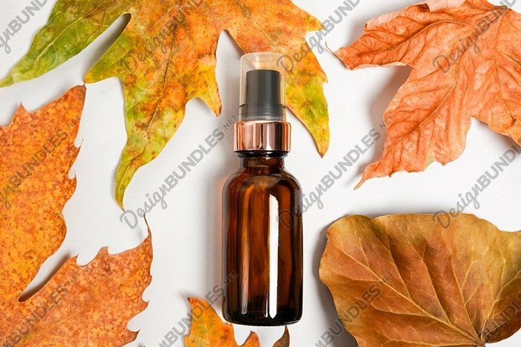 Brown cosmetic dropper bottle with dry falling leaves