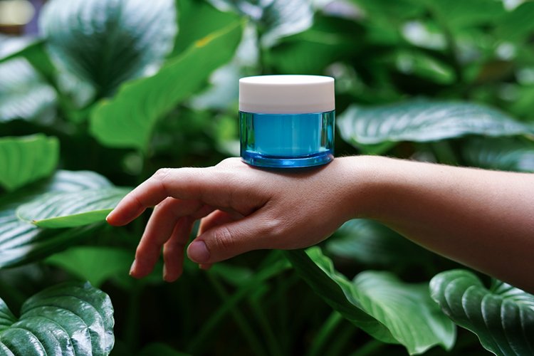 A blue jar with cosmetic cream staying on female hand