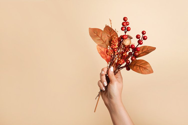 female hand holding autumn bouquet with red leaves