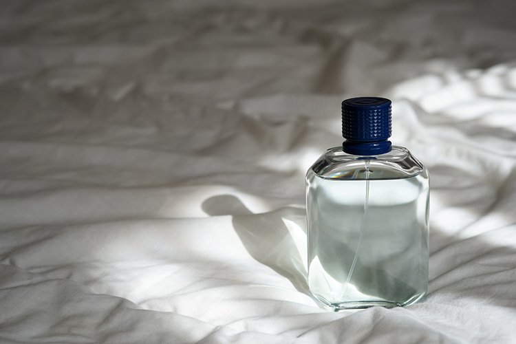 Male blue perfume bottle on the white bed with shadows