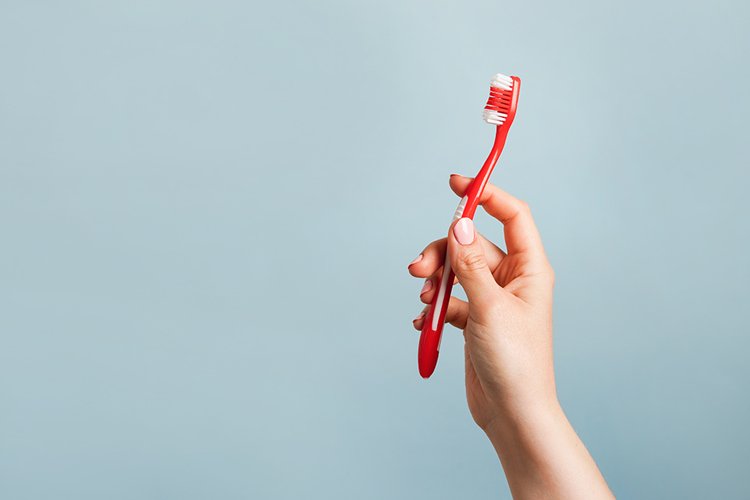 Woman holding red toothbrush against color blue background