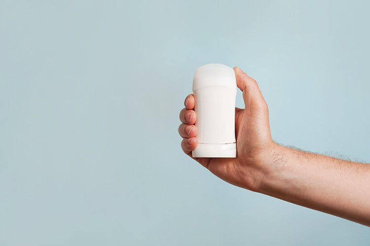 Male hand holding white deodorant on blue background