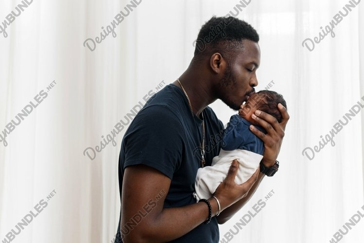 Young african american dad kisses little mestizo baby.