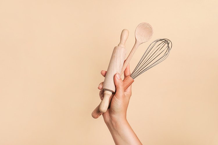 hand holding kitchen utensils for food and bakery on beige