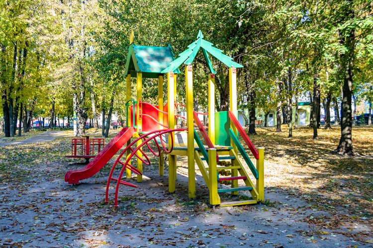 Empty playground with metal slide for kids on nature