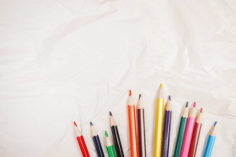 multicolored pencils on white crumpled paper, copy space