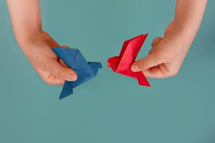 red and blue paper origami pigeons in children's hands