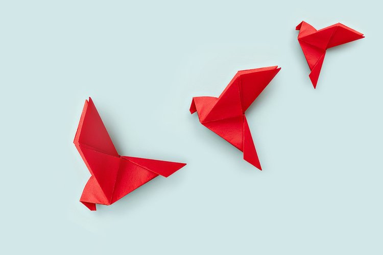 three red paper origami pigeons on pastel blue background