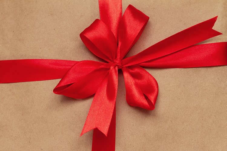 gift in brown craft paper and red ribbon with bow, close up